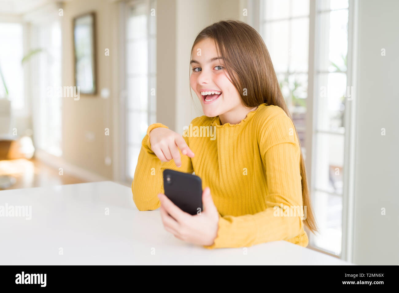 Beautiful young girl kid sending a message using smartphone very happy ...