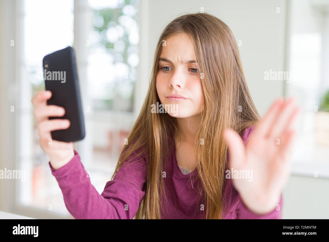 Beautiful young girl kid sending a message using smartphone with open ...