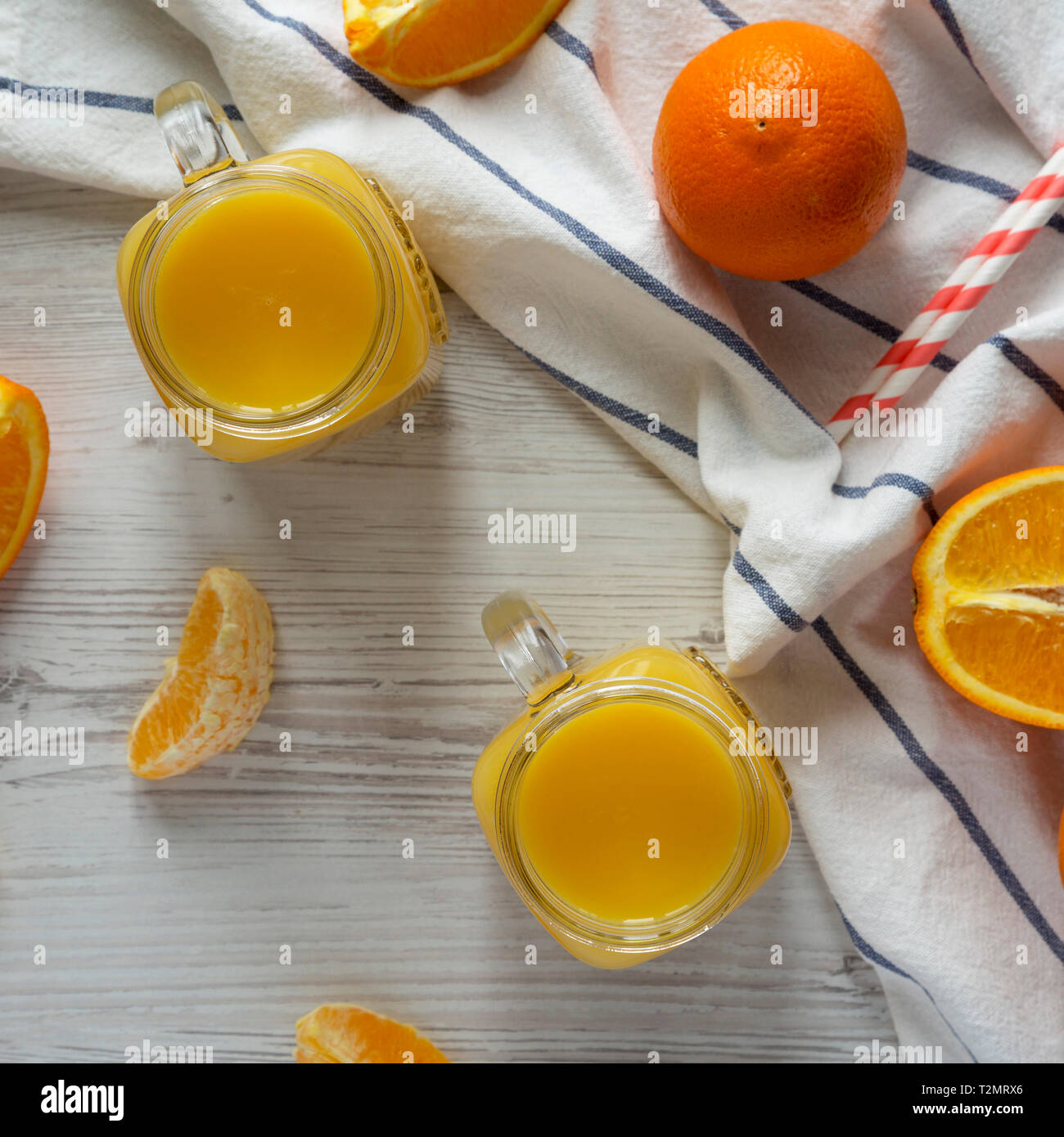 Fresh orange juice in glass jars over white wooden surface, overhead ...