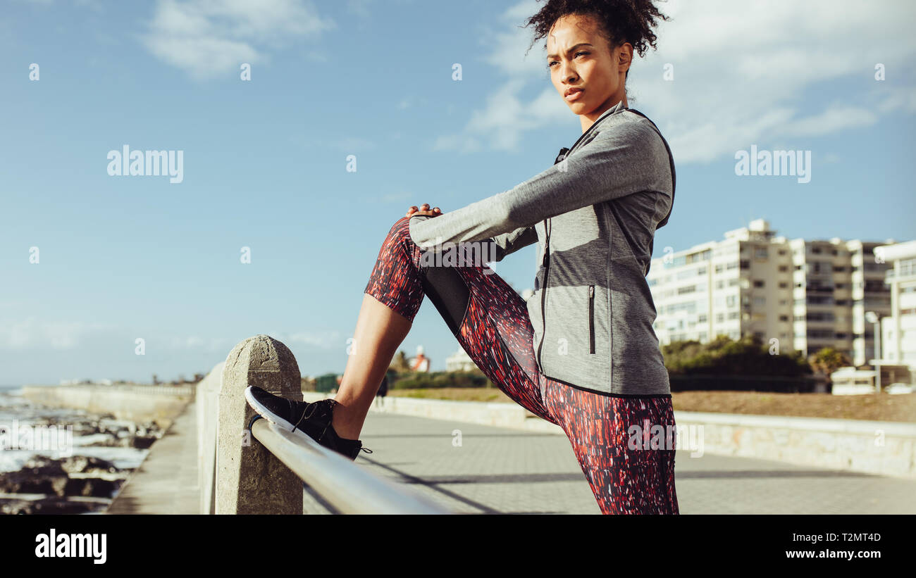 Active young woman stretching and warming up on the promenade along the ...