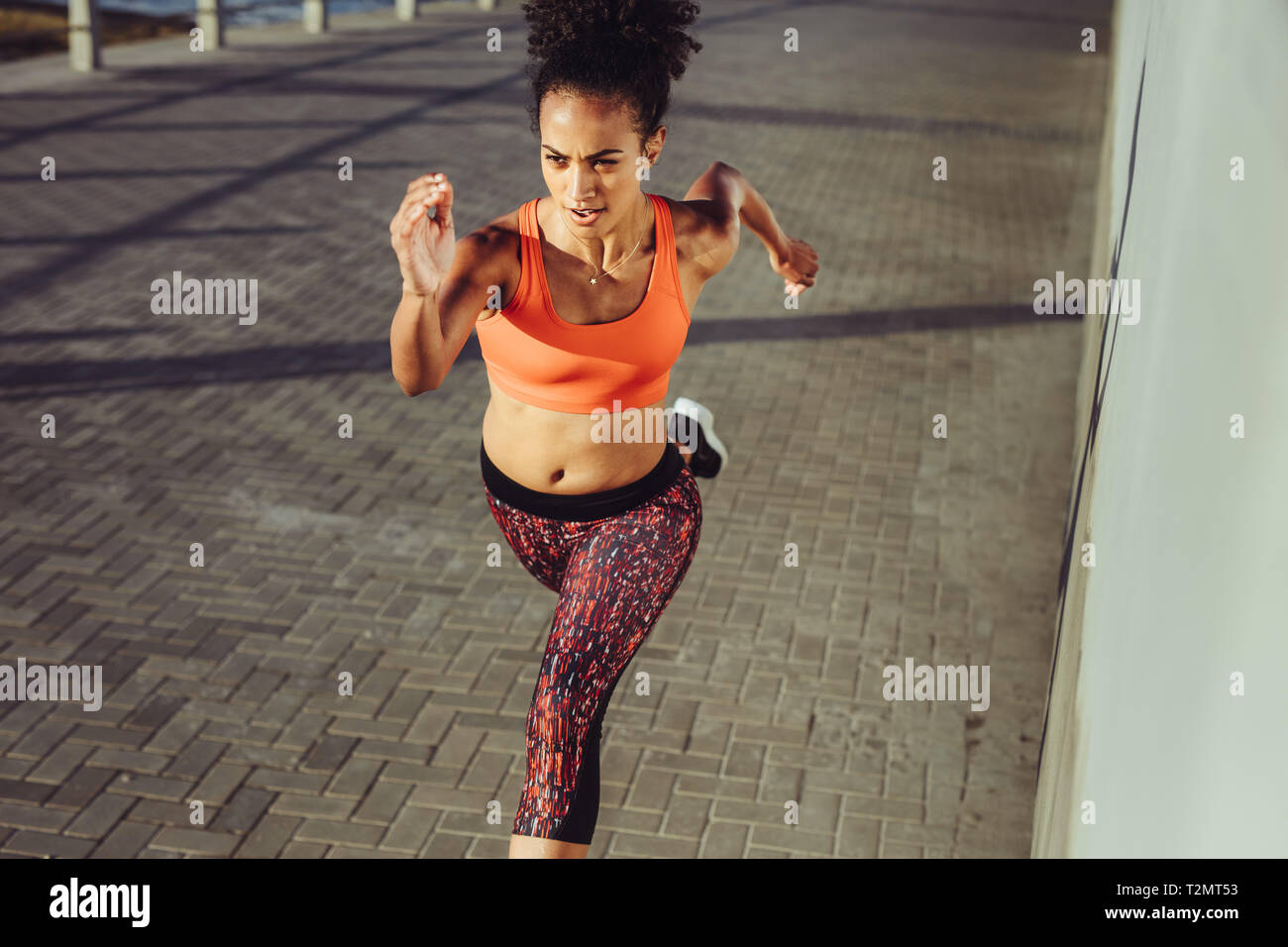 Fit young woman sprinting on the pavement. Female in sportswear running ...