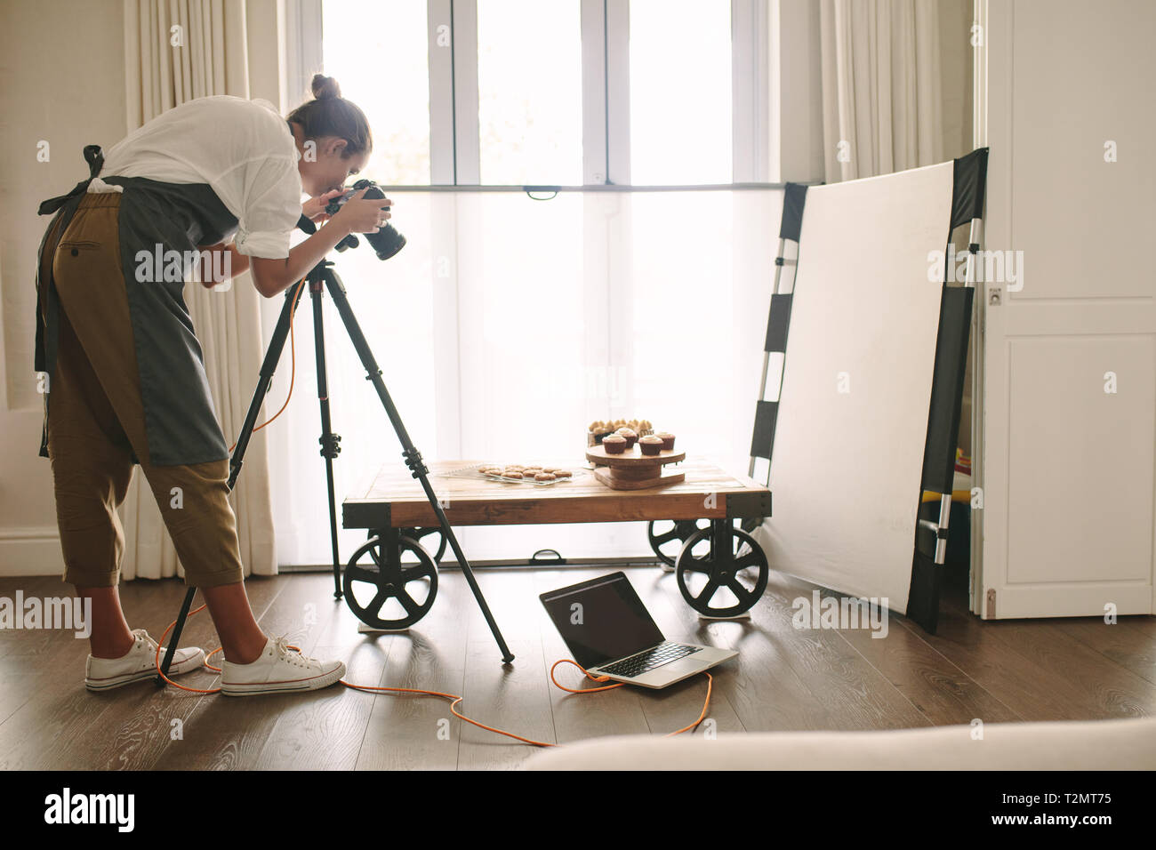 Professional food blogger taking pictures of pastry items on table with ...