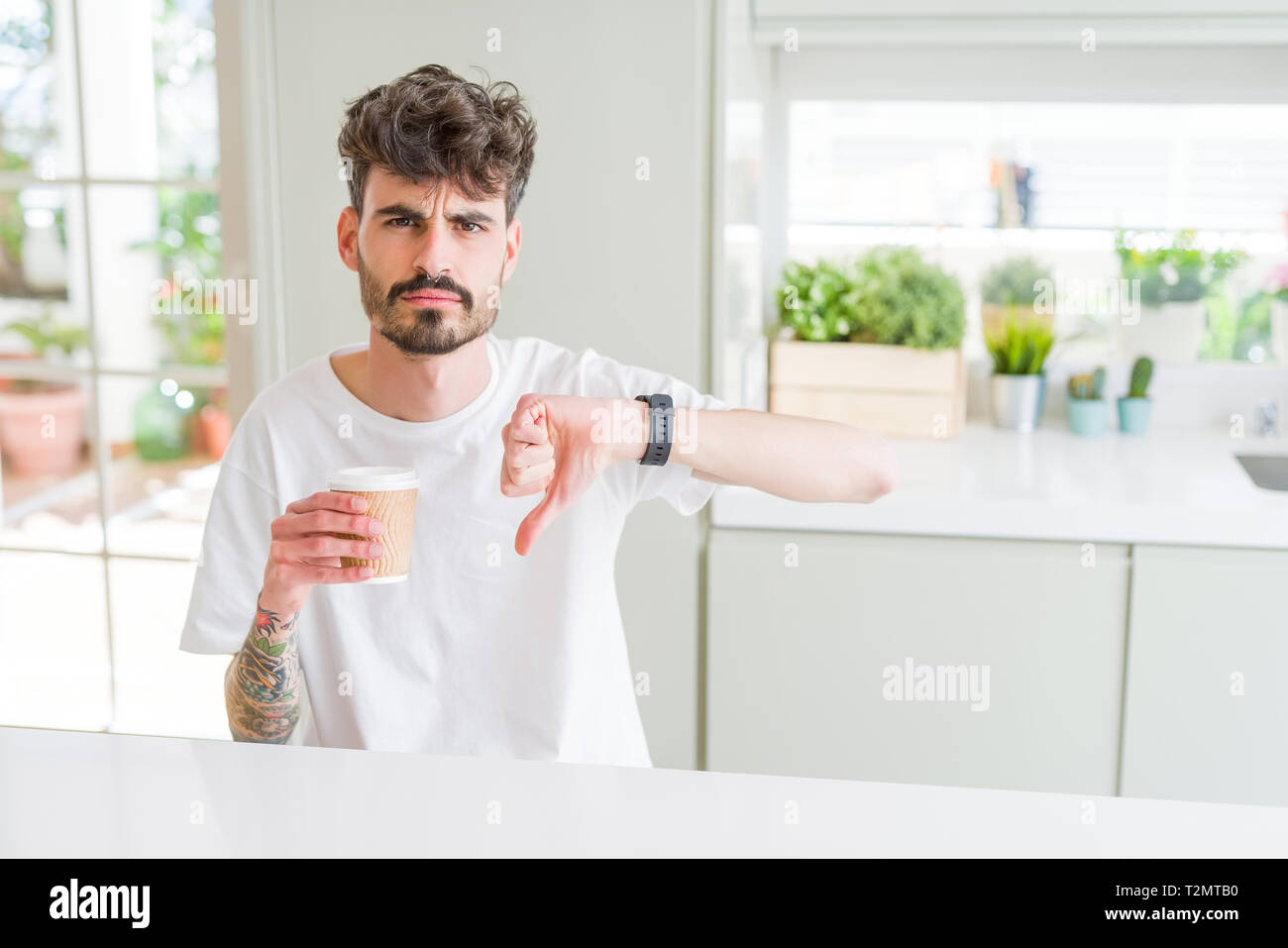 Young man drinking a coffee in a paper cup in the morning with angry ...