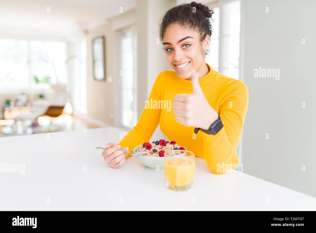 Young african american girl eating healthy cereals for breakfast happy with big smile doing ok ...