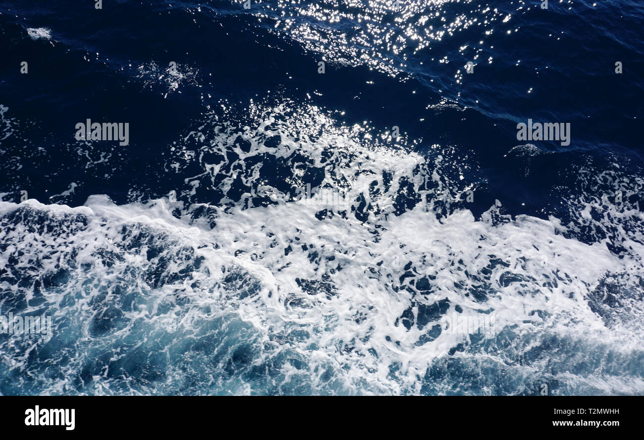 Dark blue deep sea surface, rippled water with sea foam and sparkling ...
