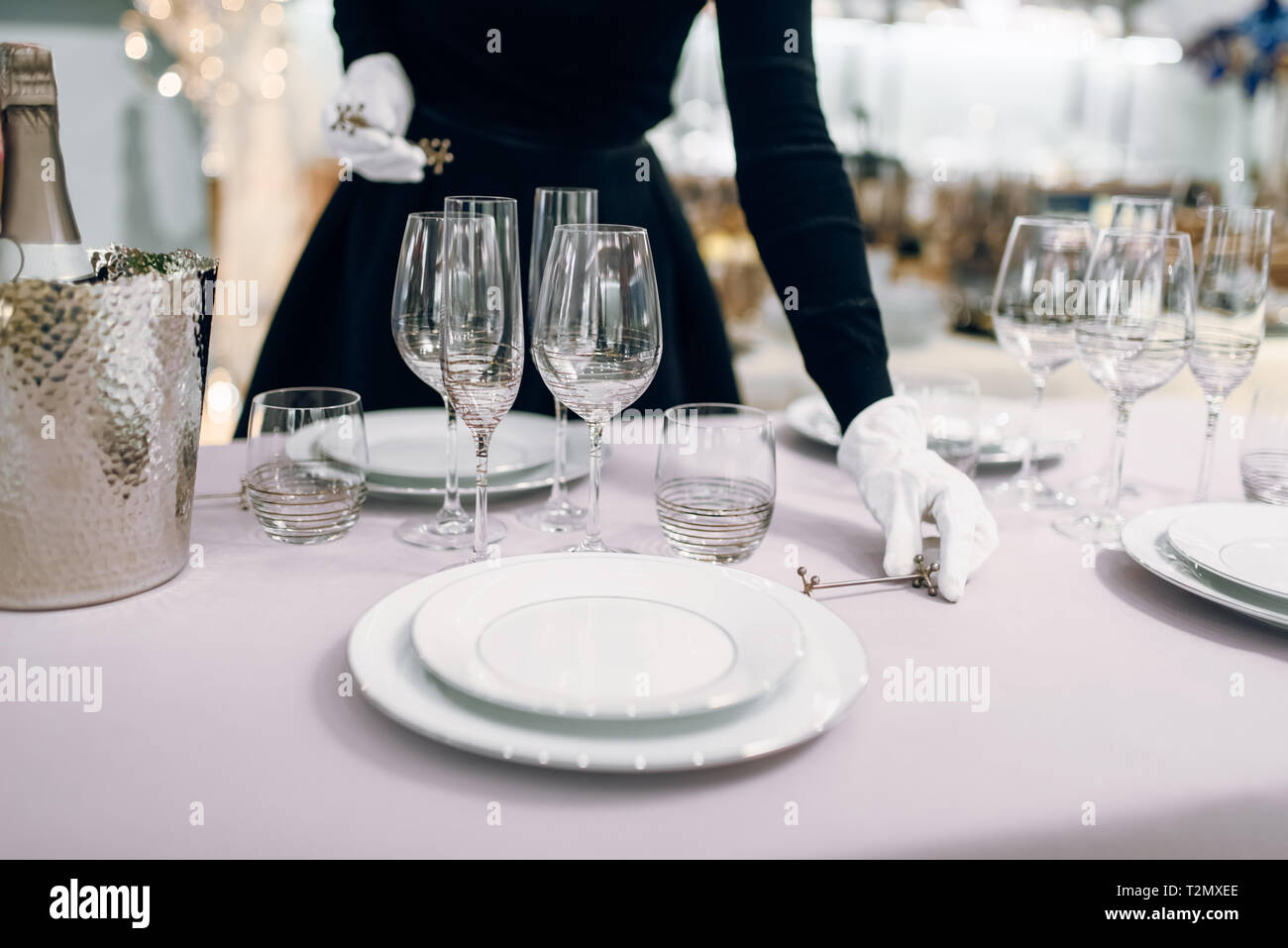Waitress in gloves puts the knife, table setting. Serving service ...