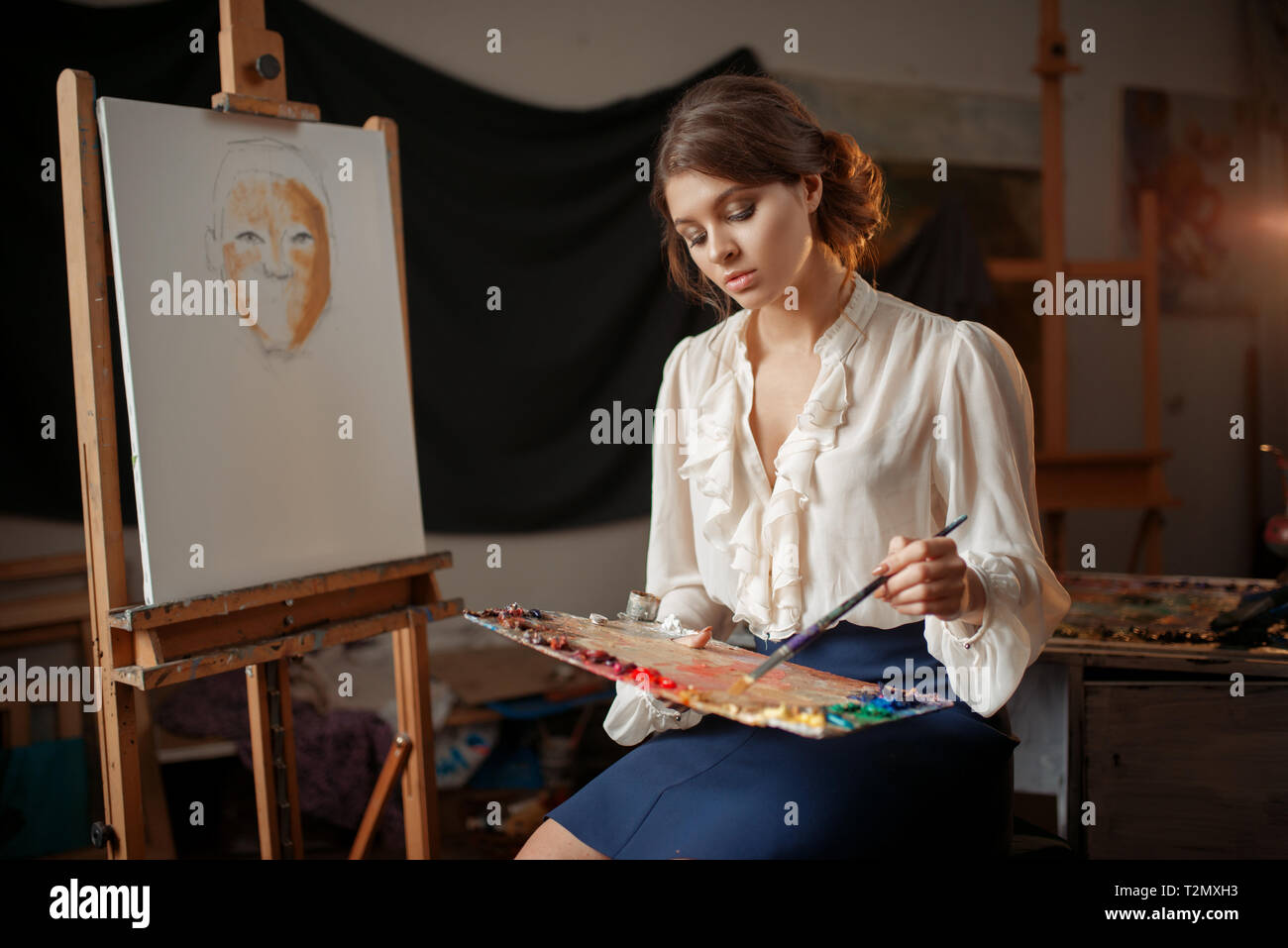 Female painter holds color palette and brush in studio. Creative ...