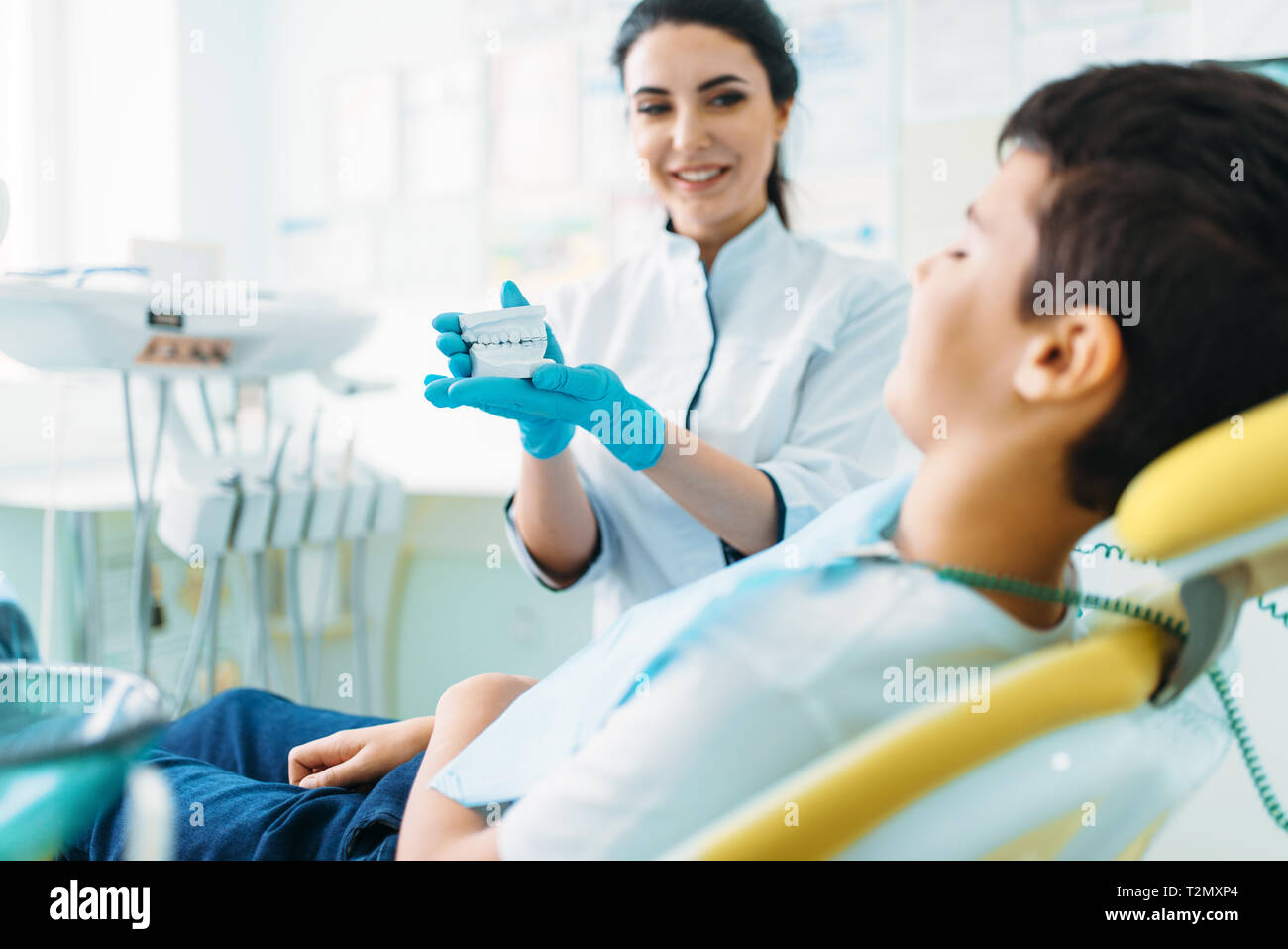Female dentist shows dentures to little boy in a dental chair ...