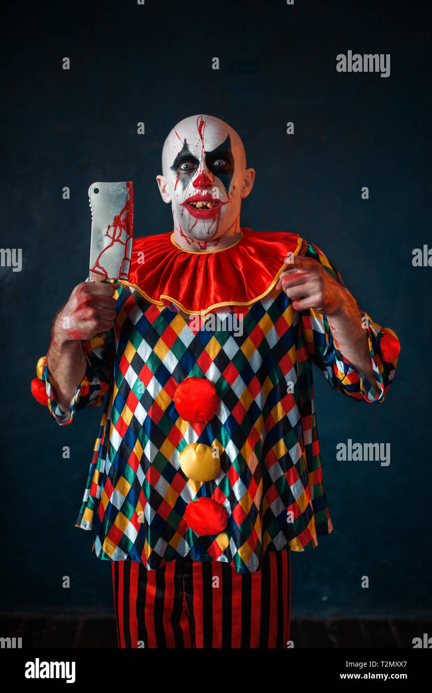 Mad bloody clown with meat cleaver and baseball bat, circus horror. Man ...