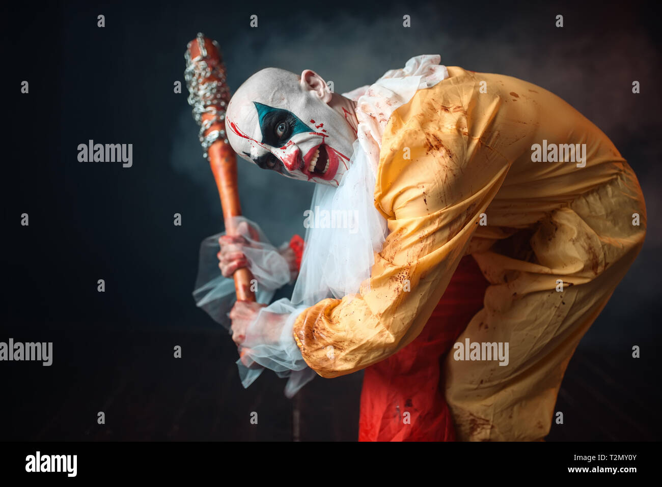 Scary bloody clown with crazy eyes holds baseball bat. Man with makeup ...