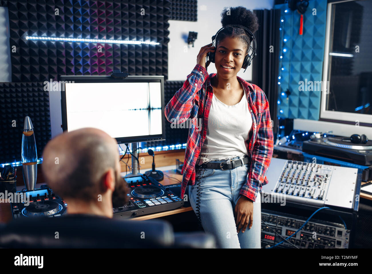 Sound producer and female performer in headphones listens composition ...