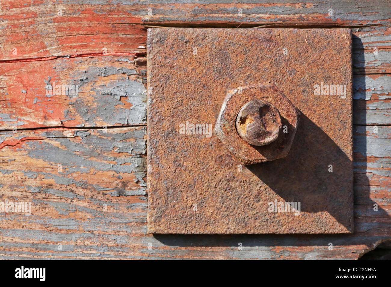 Large rusty nut holds wood aged painted planks together background ...