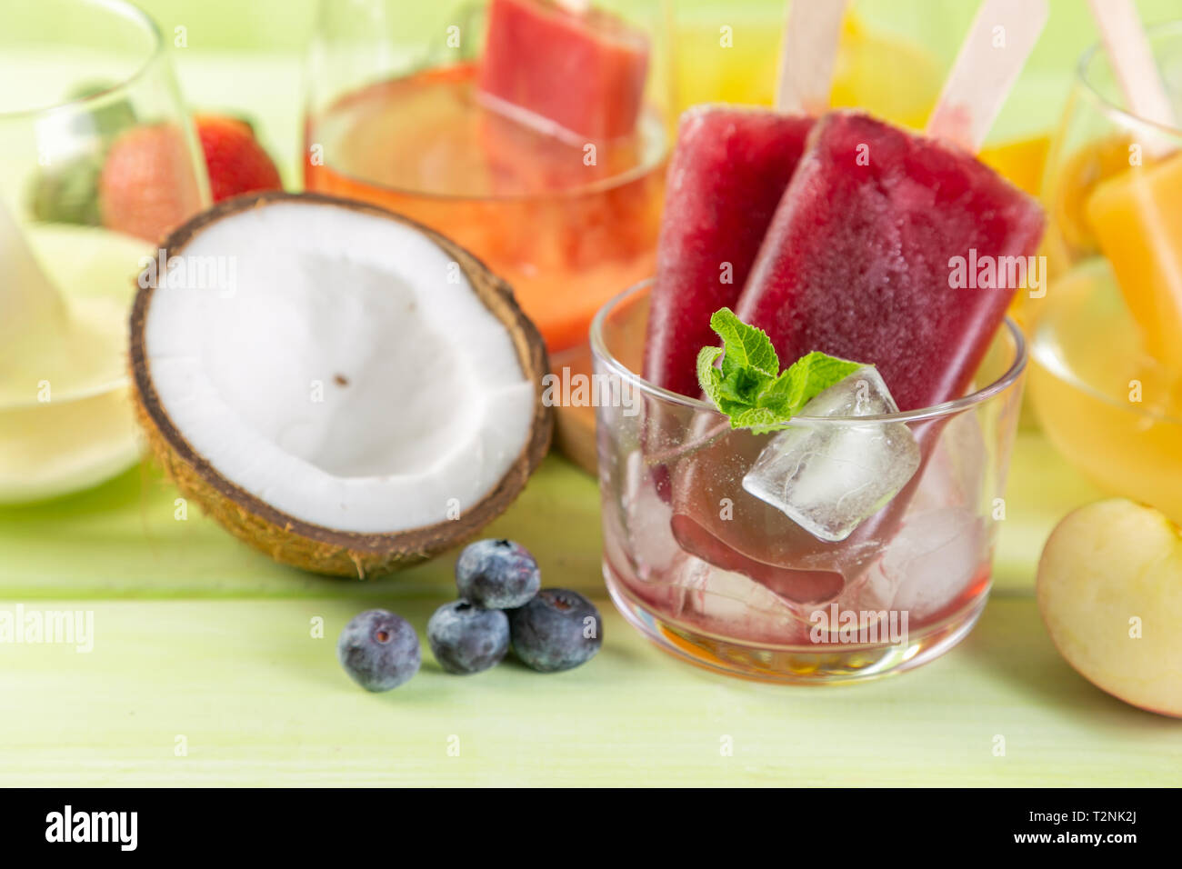 Selection of colourful ice pops and ingredients on green wood ...