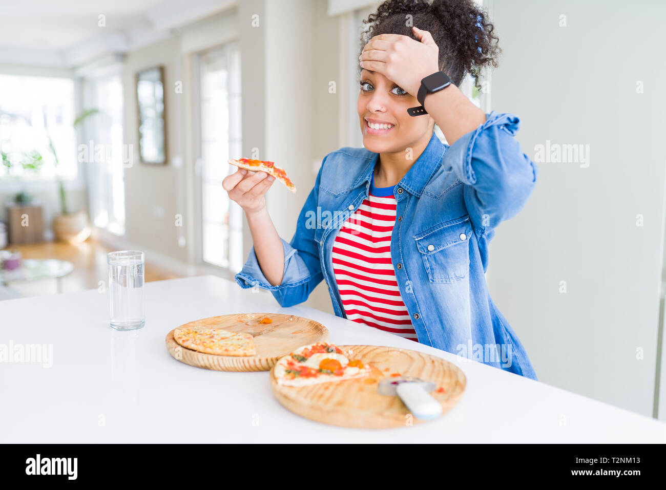 Young african american woman eating two homemade cheese pizzas stressed ...