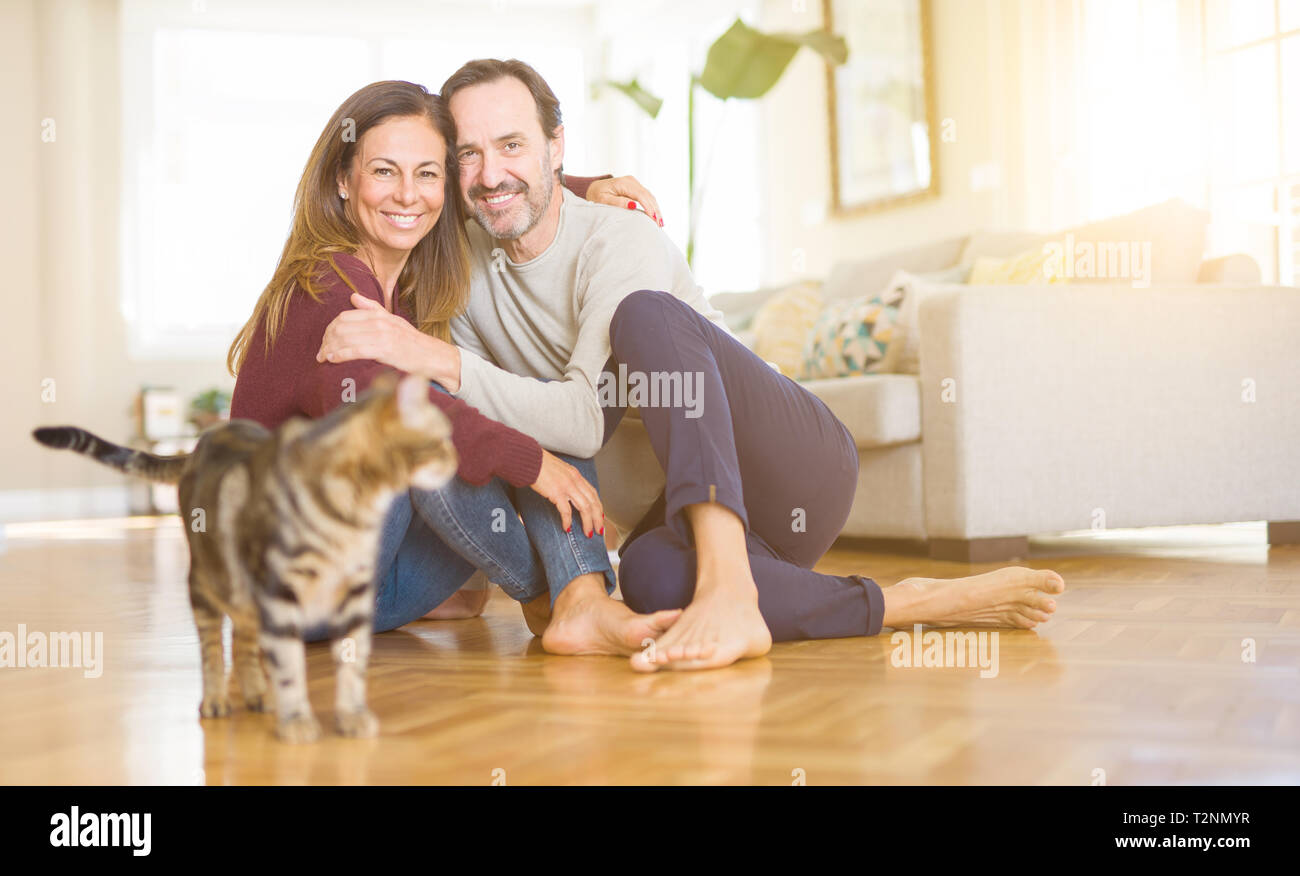 Beautiful romantic couple sitting together on the floor with the cat at ...