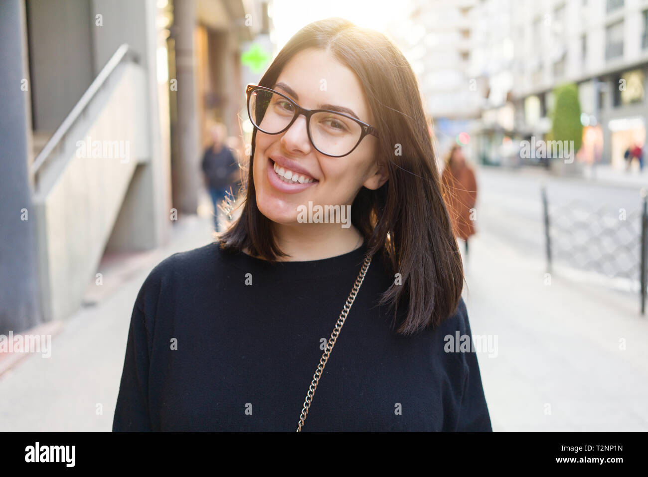 Beautiful young brunette woman smiling excited walking down the city ...