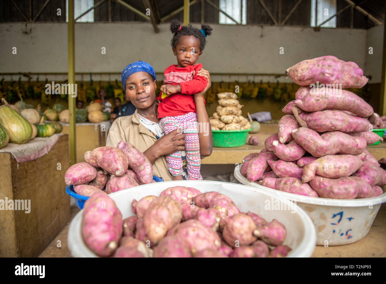 Mother holds up her child at outdoor market, Rwanda Farmers Market, in ...