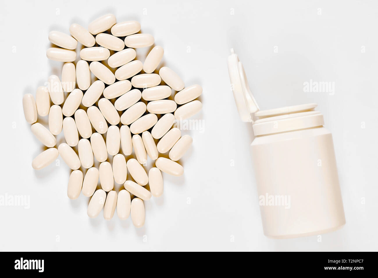 Oval tablets beige color are on a white background with an open bottle ...