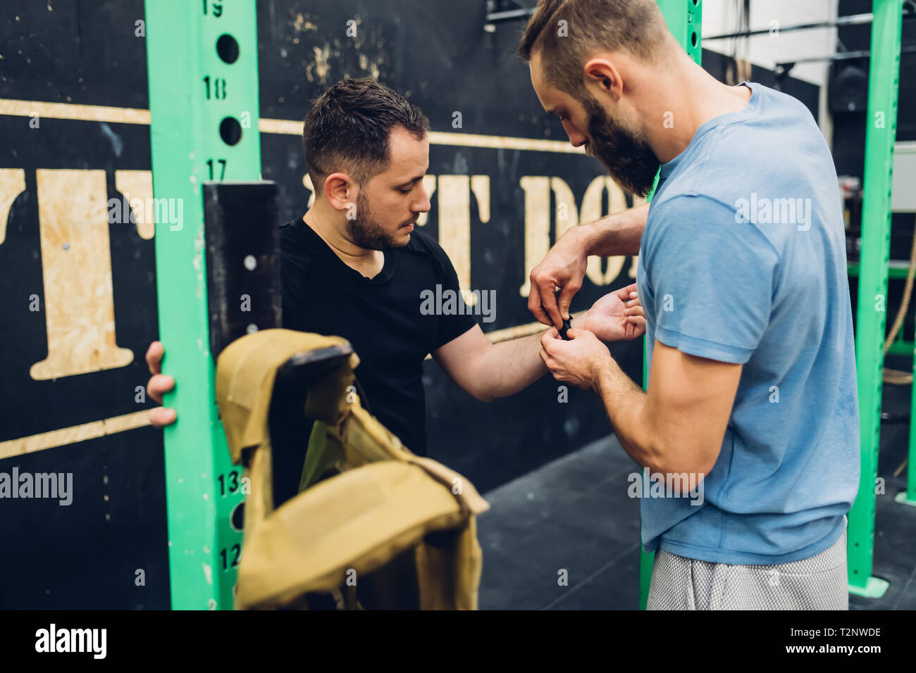 Personal trainer helping man in gym Stock Photo - Alamy