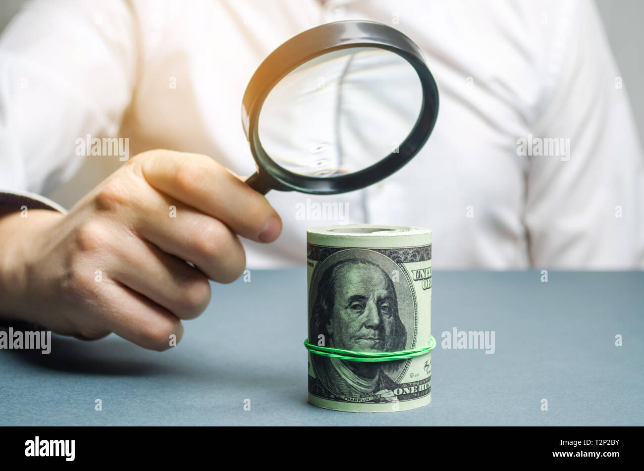 Businessman holding a magnifying glass over the dollars. Analysis of ...