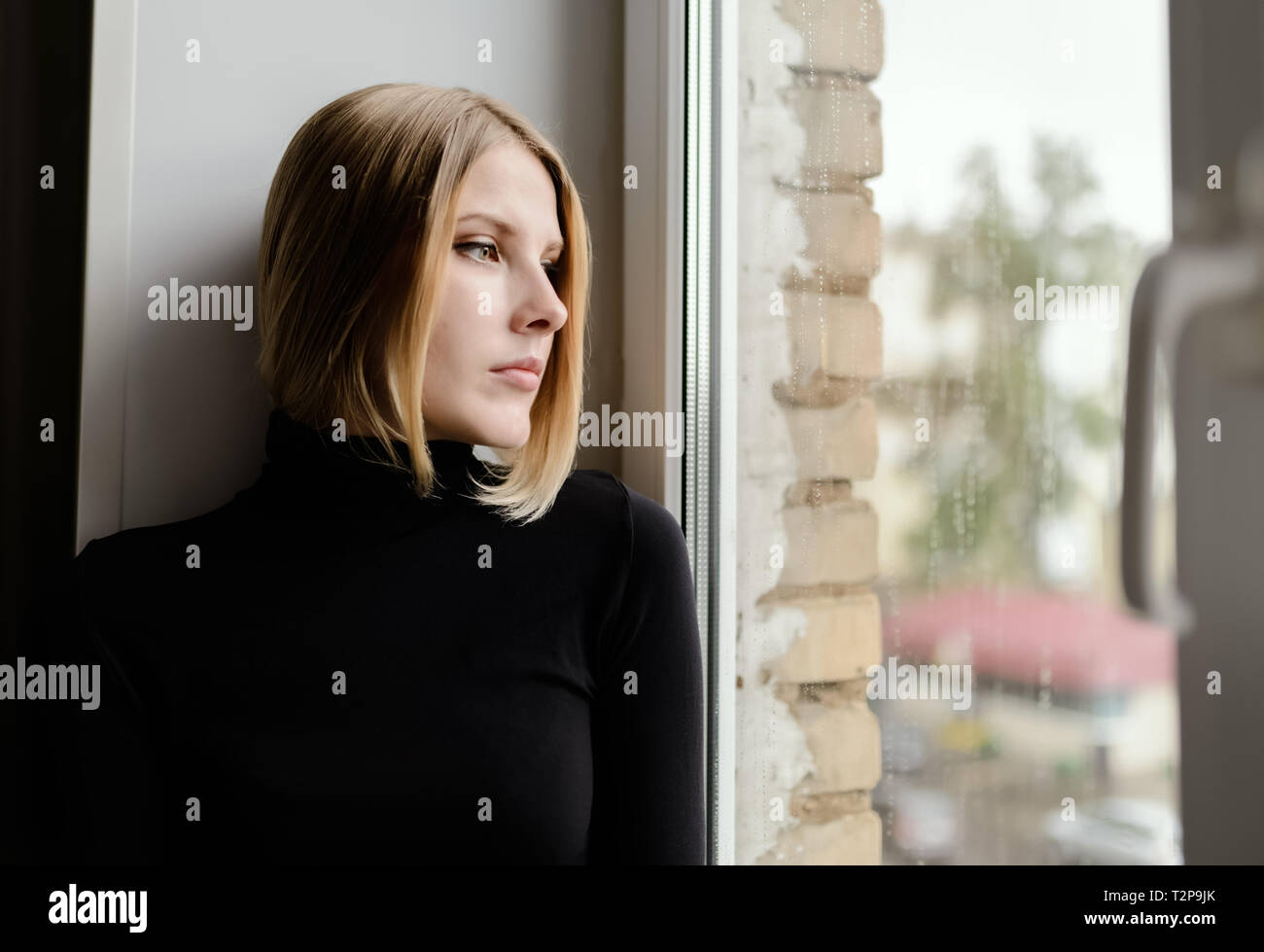 Sad woman looking through the glass window with a rain drops Stock ...