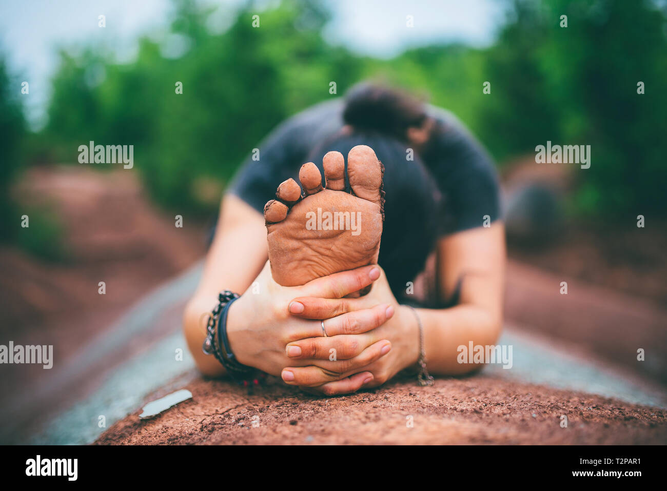 Woman sitting and bending forward on rock Stock Photo - Alamy