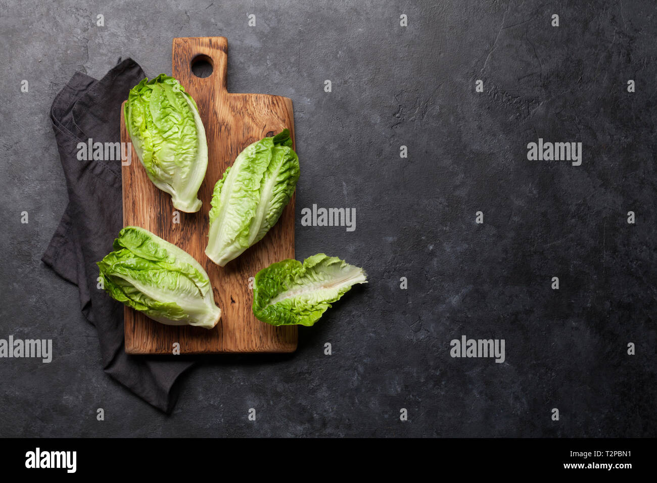 Mini romaine lettuce salad on stone kitchen table. Top view with copy ...