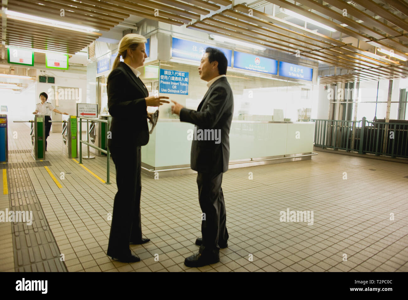 Businessman and businesswoman having a conversation outside a ticketing ...