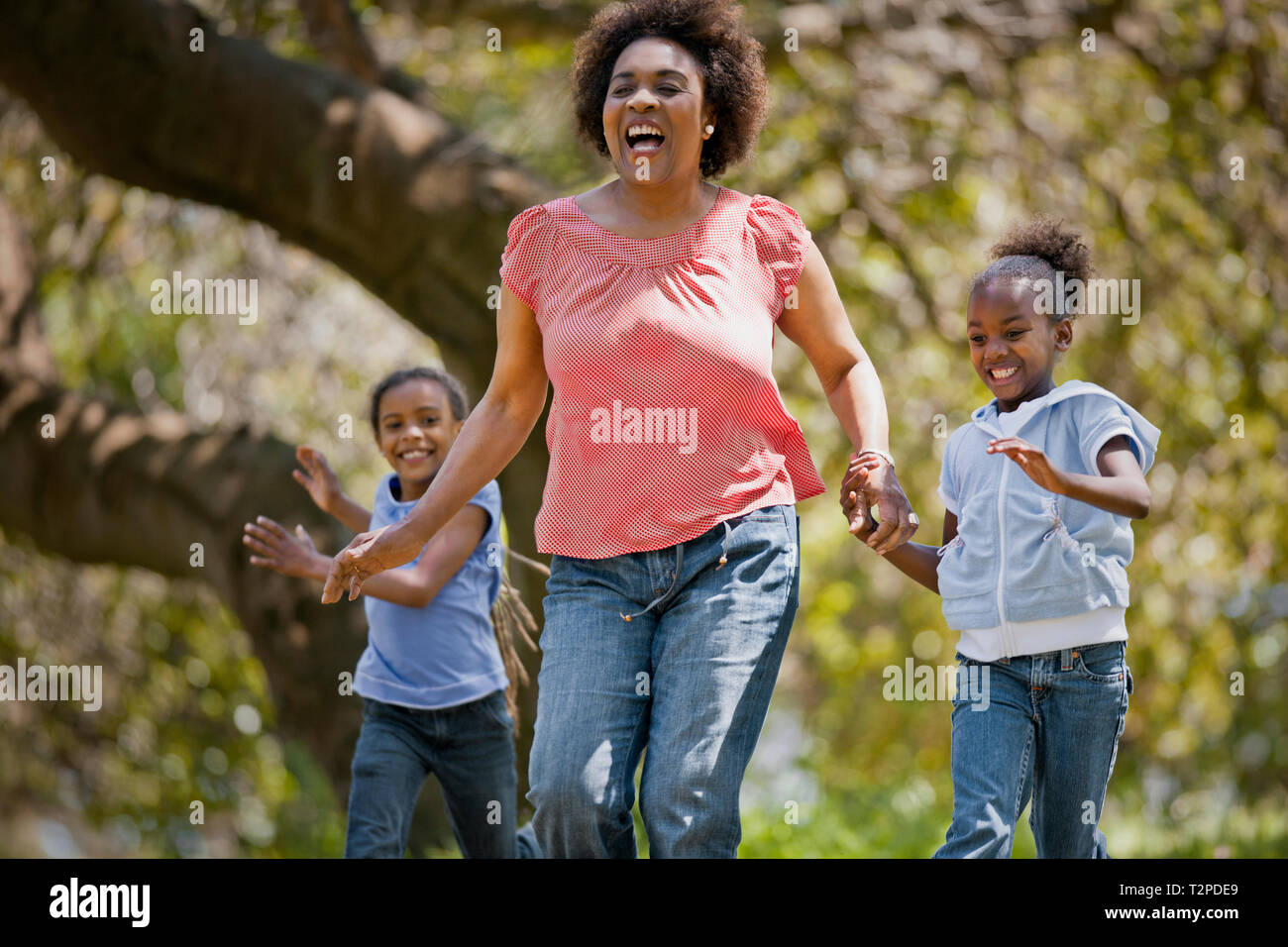 Happy mature woman running hand in hand with her two granddaughters ...