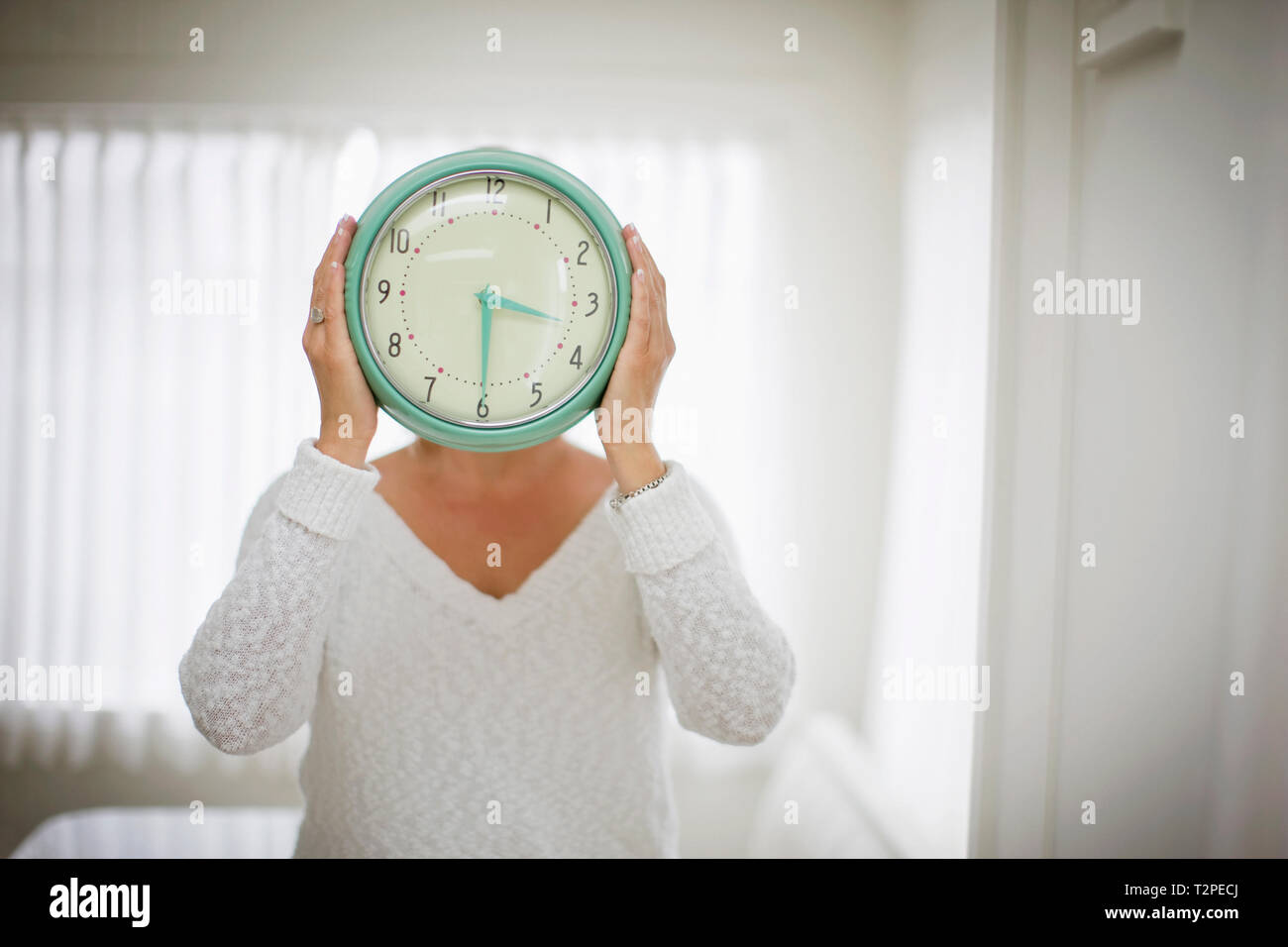 Woman holding clock in front of face Stock Photo - Alamy