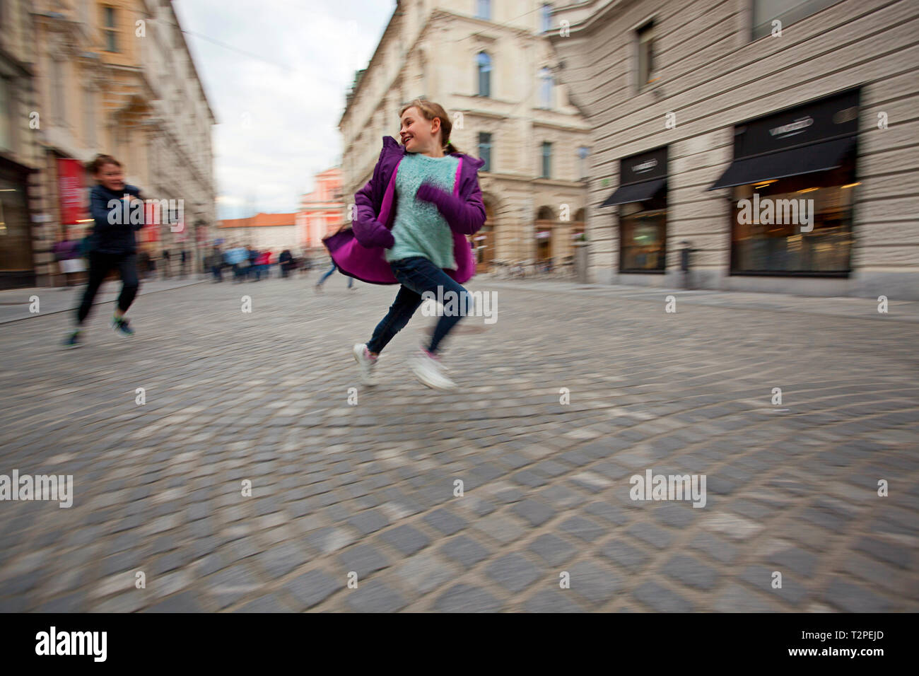Young boy chasing girl in the street, Ljubljana, Slovenia Stock Photo ...