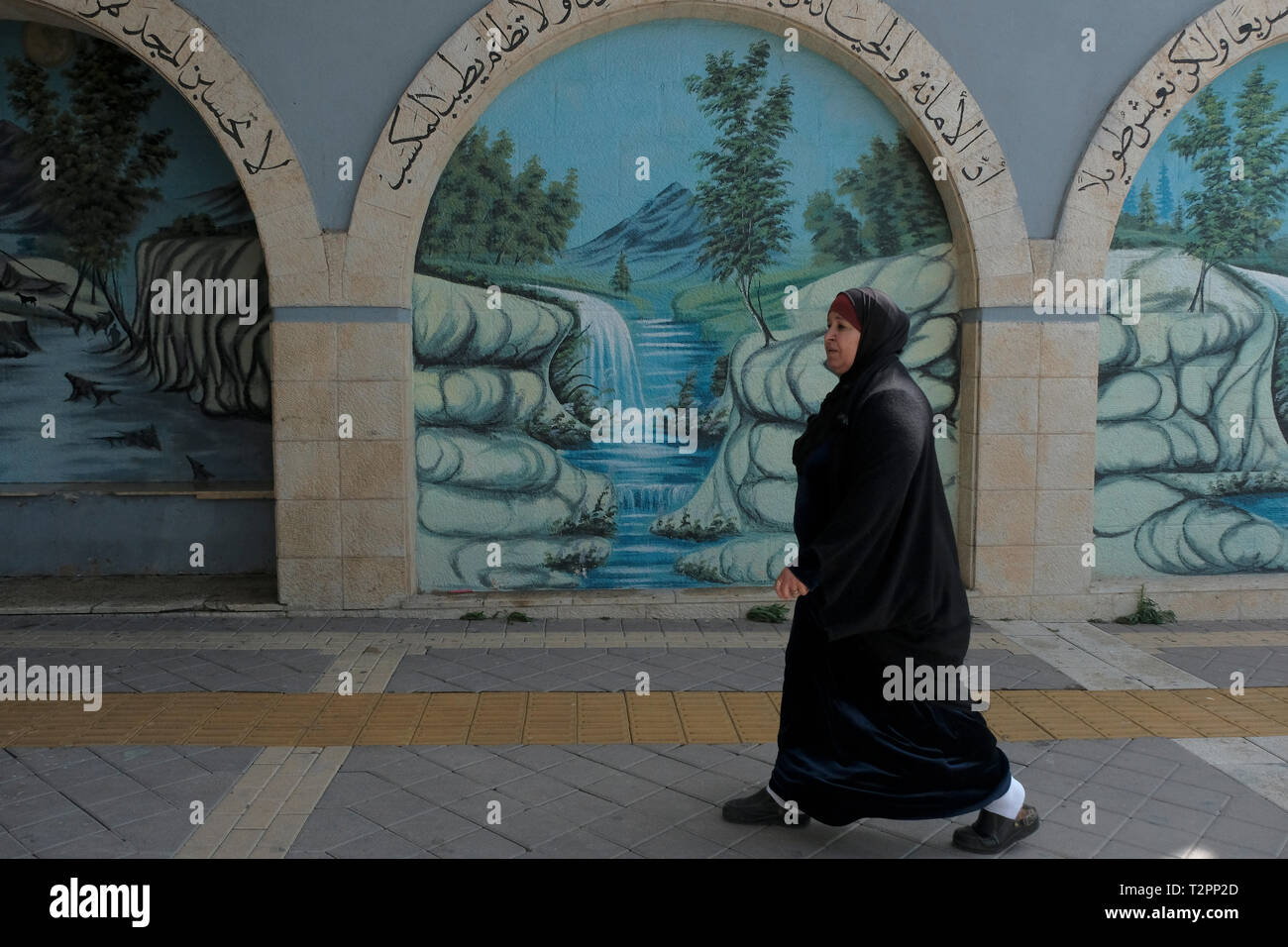 A Bedouin woman walks past a painted wall in Rahat a predominantly ...