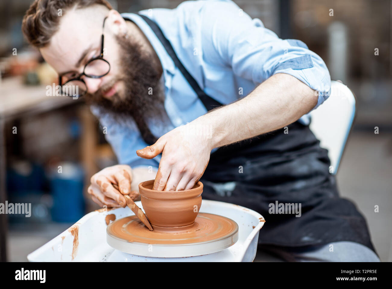 Handsome man as a potter worker in apron making clay jugs on the ...