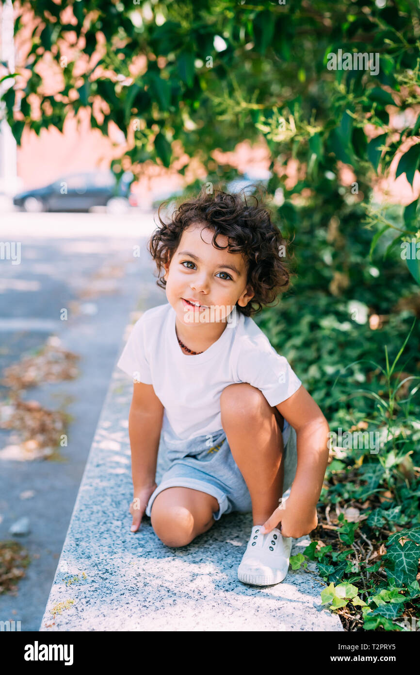 Toddler resting under tree in park Stock Photo - Alamy