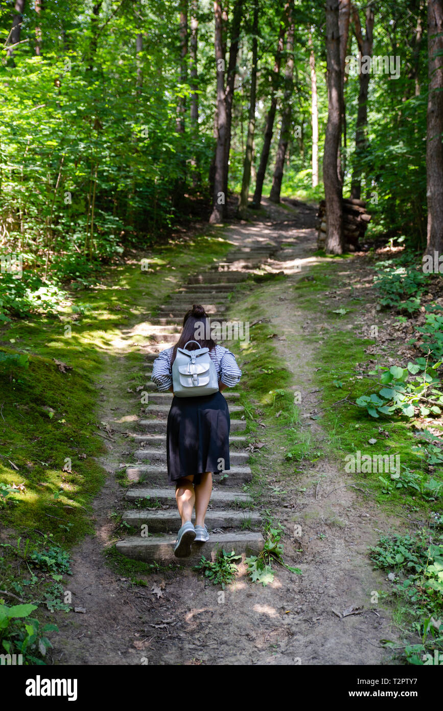 woman walking up by old stairs in forest. view from behind Stock Photo ...