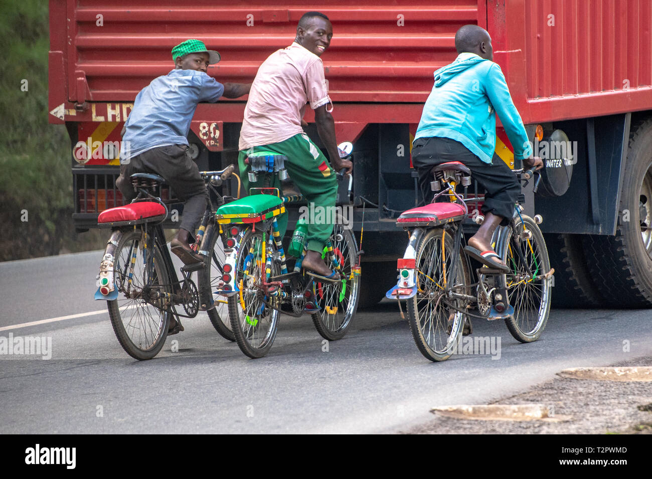 Cyclist hitch a ride from a truck going up hill in northwest Rwanda ...