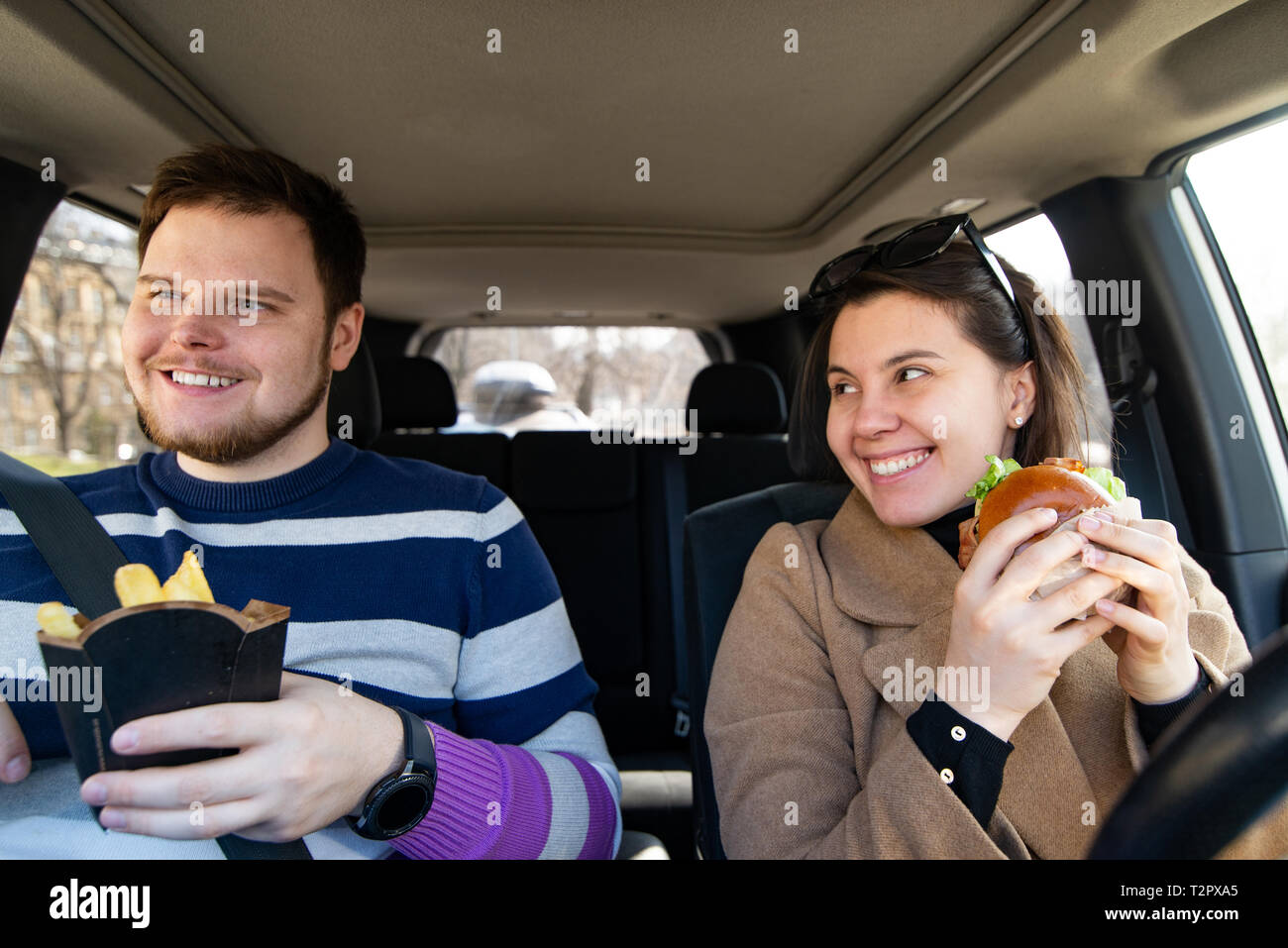 young couple eating fast food in car. modern rhythm lifestyle Stock ...