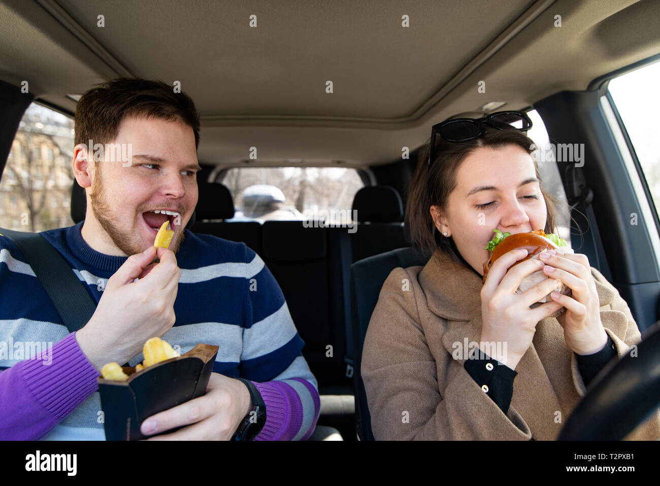 young couple eating fast food in car. modern rhythm lifestyle Stock ...