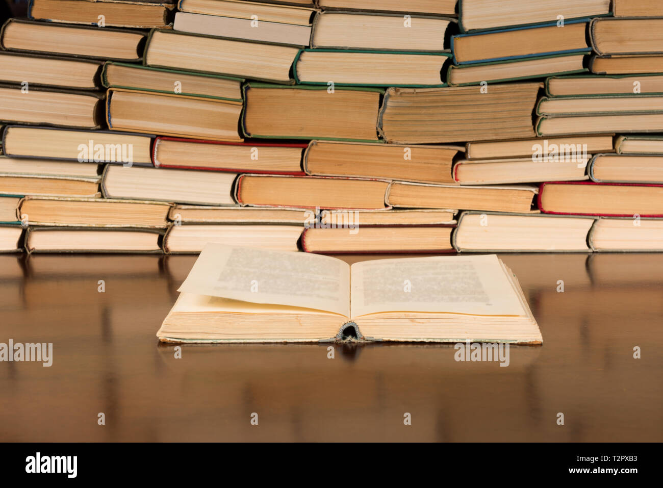 Open book on the desk with background of book piles Stock Photo - Alamy