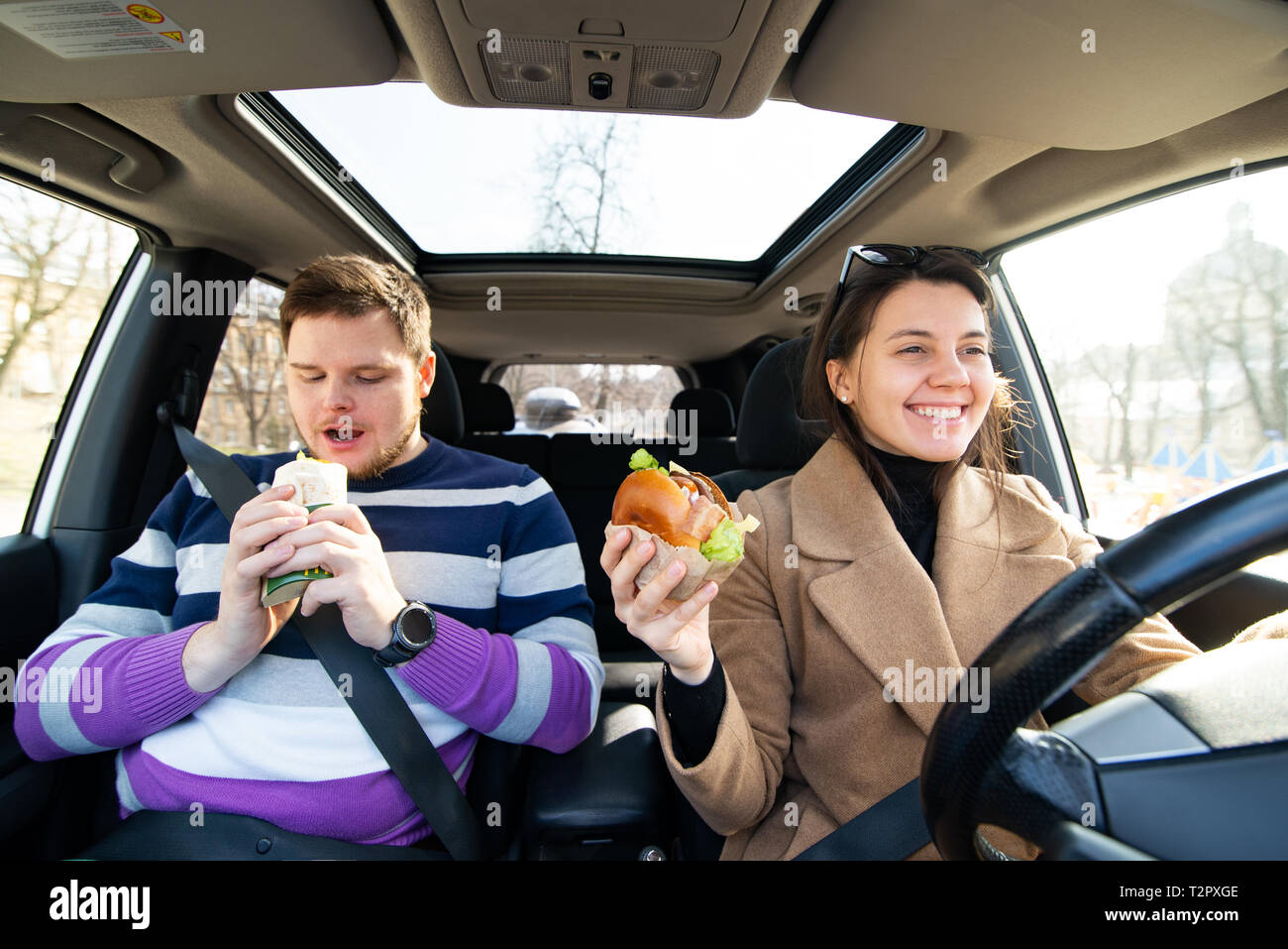 young couple eating fast food in car. modern rhythm lifestyle Stock ...