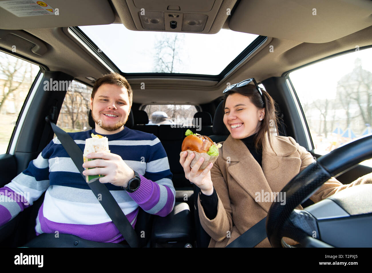 young couple eating fast food in car. modern rhythm lifestyle Stock ...