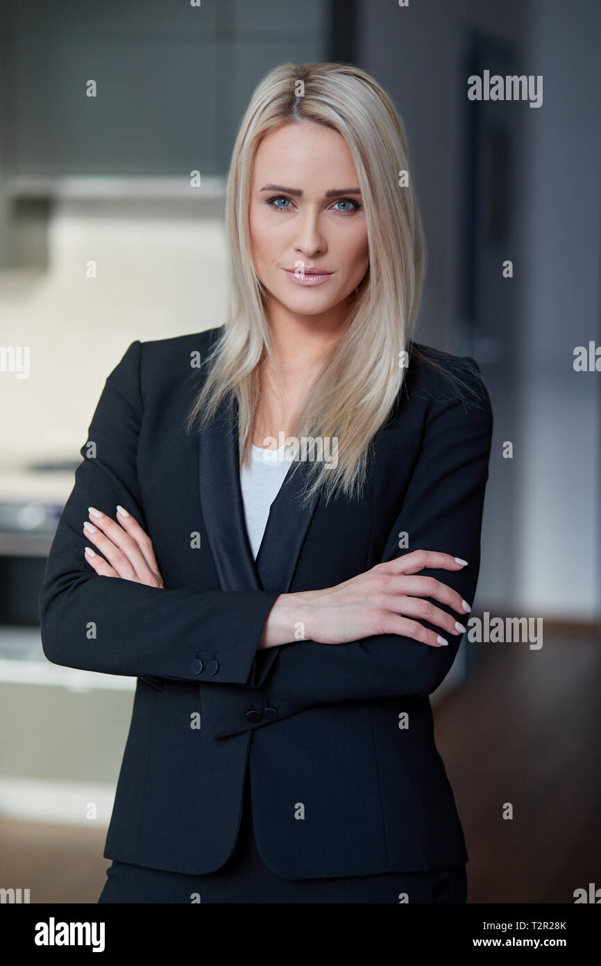 Nice and calm blond, middle age business woman standing at her office ...