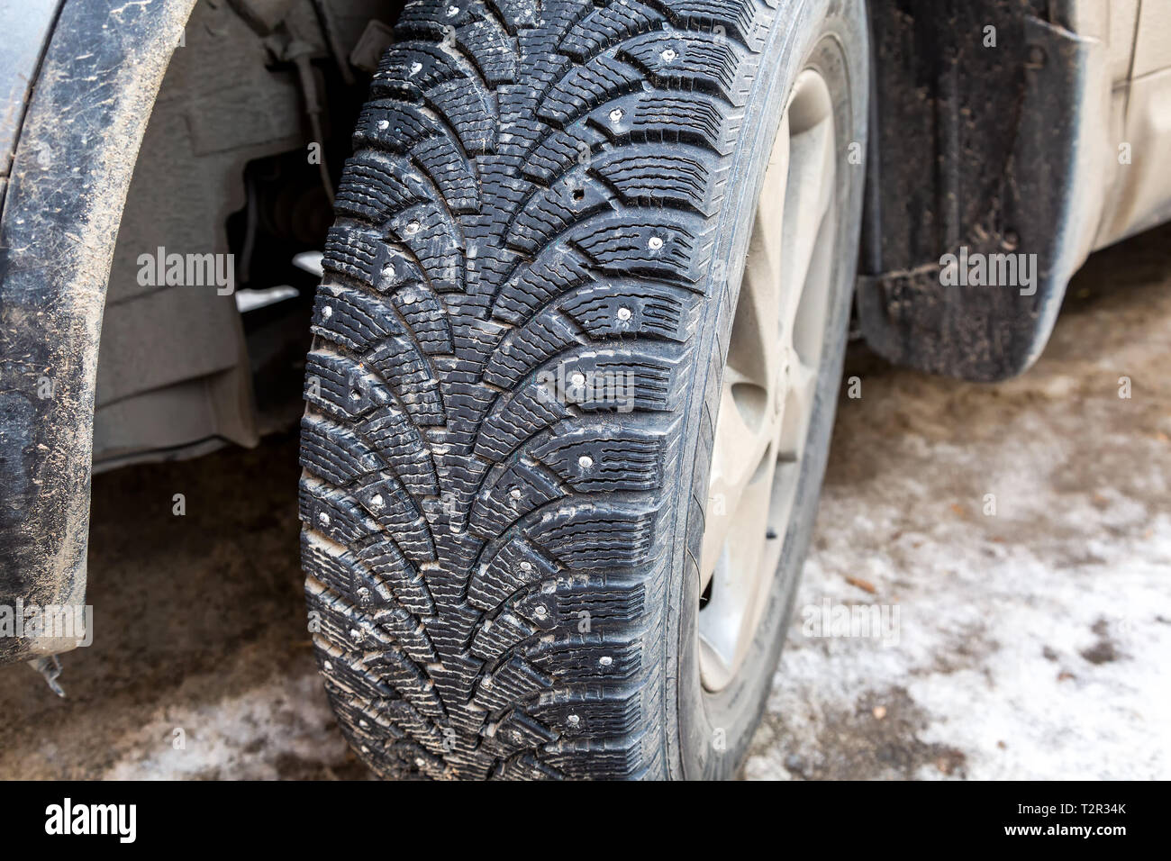 Used winter studded car wheel on the snow Stock Photo - Alamy
