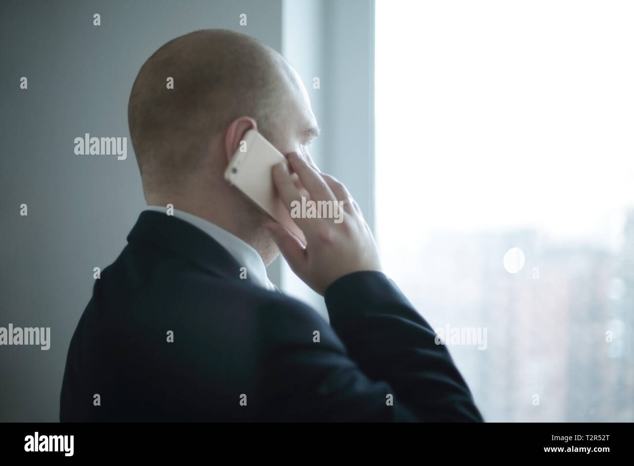 rear view .businessman with smartphone looking out the window of the ...