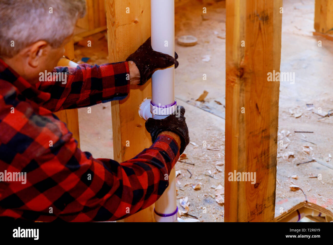 Plumber installing PVC pipe at plastic drain pipe under construction of ...