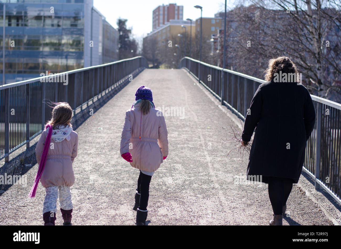 Family out for a walk over a bridge on a sunny day in urban scenery ...