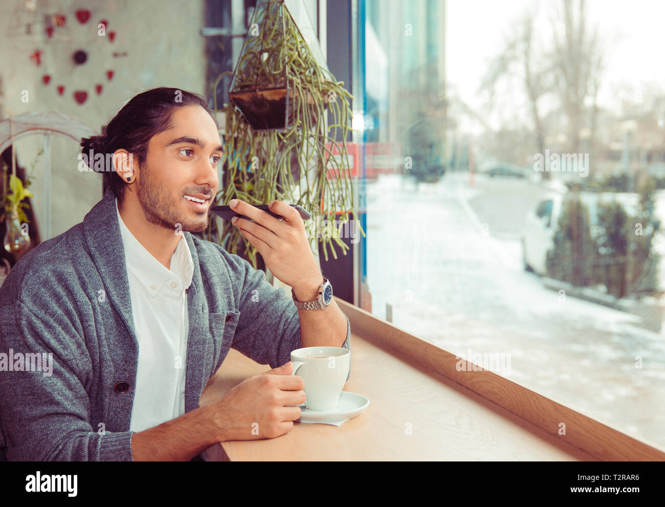 Portrait of a man using the voice recognition of the phone sitting in a ...
