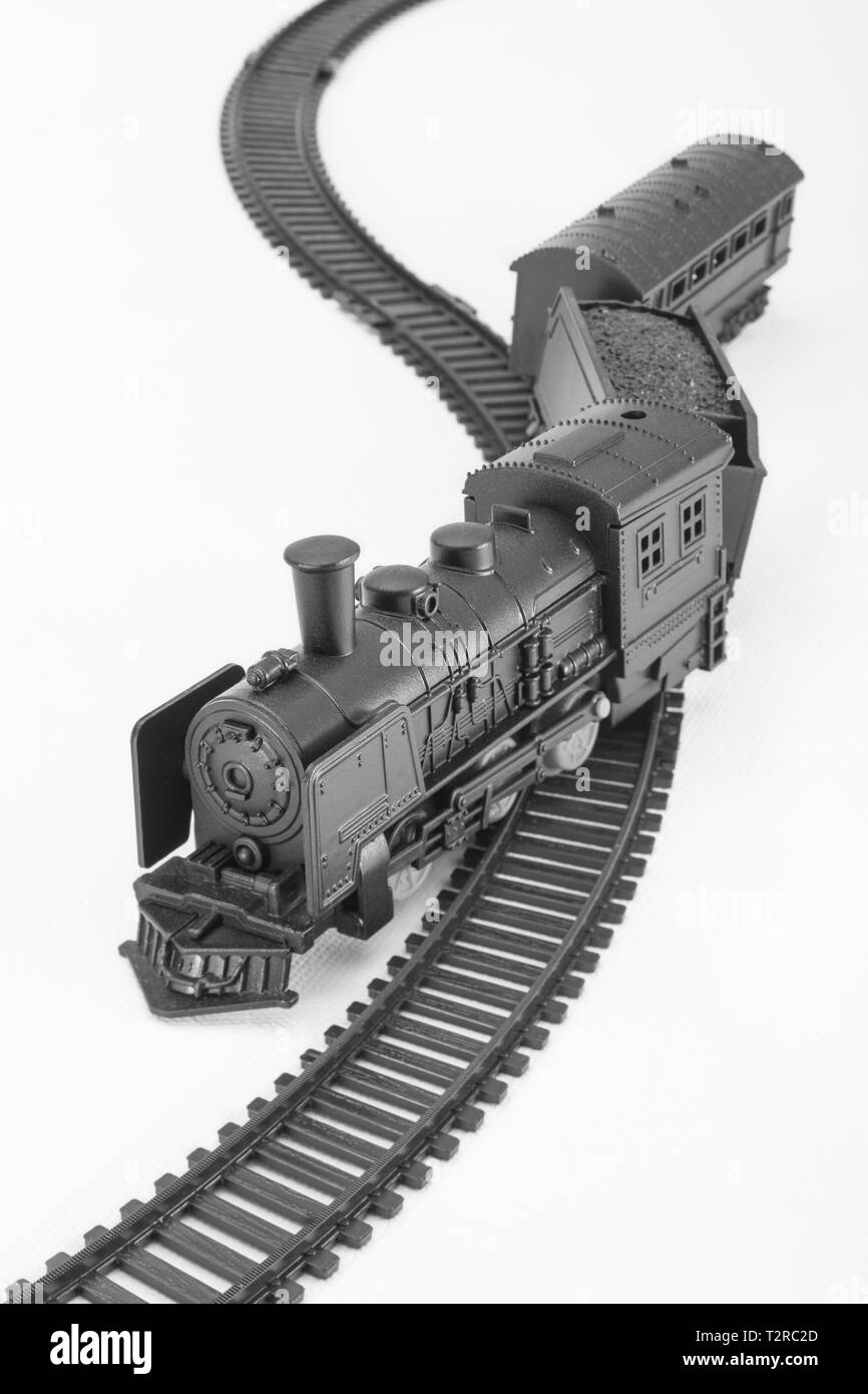 Black painted toy steam engine model. Metaphor off track, financial ...