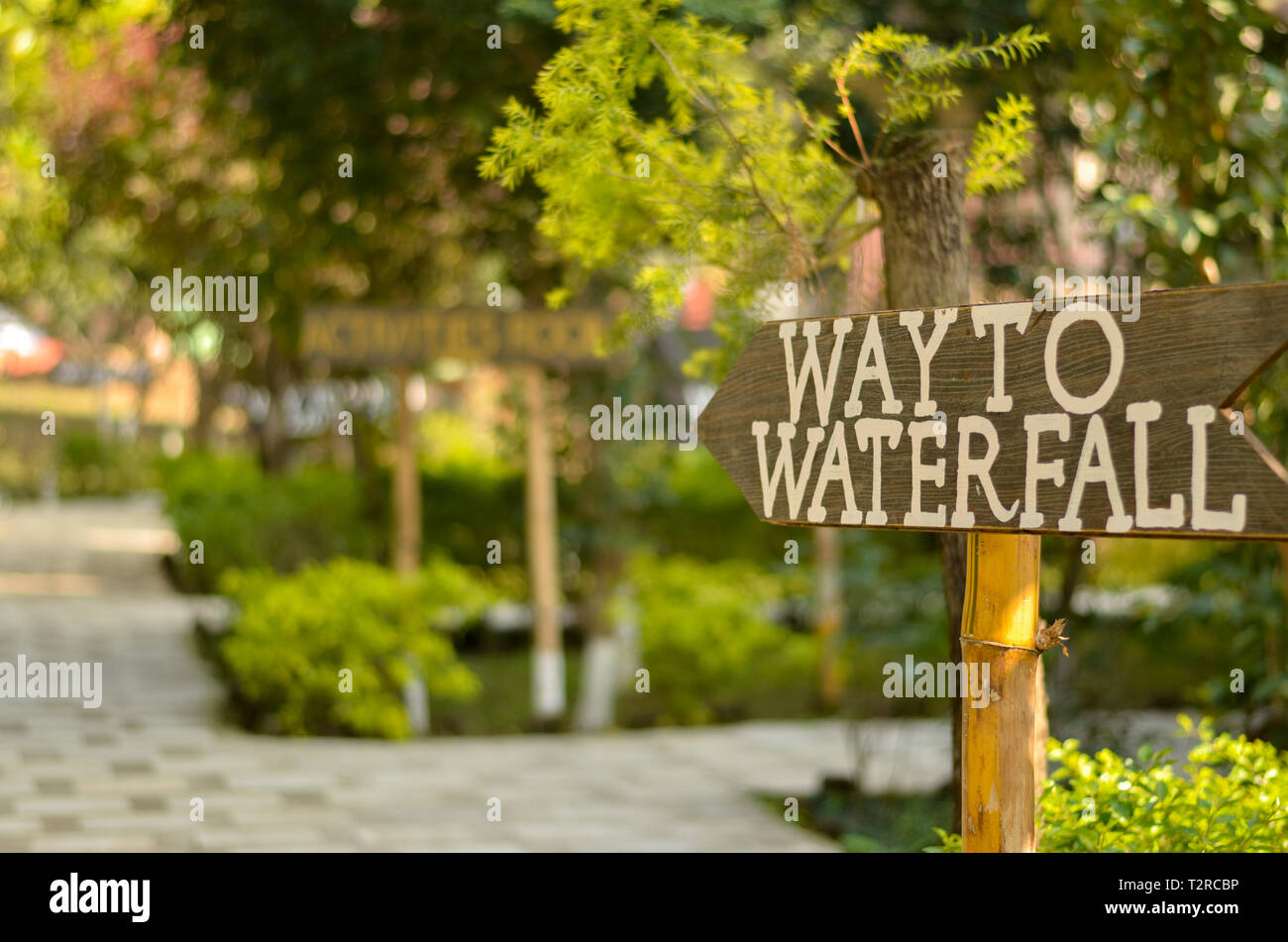 Way to waterfall signage placed on a wooden signboard in a hill resort ...