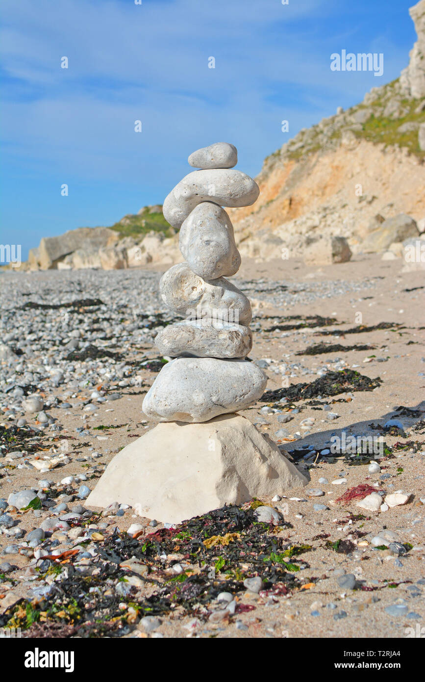 Simple rock balancing with white stones at beach in front of blue sky ...